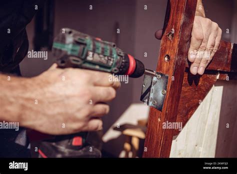 Handyman Screwing A Door Hinge In The Wooden Door Frame Home