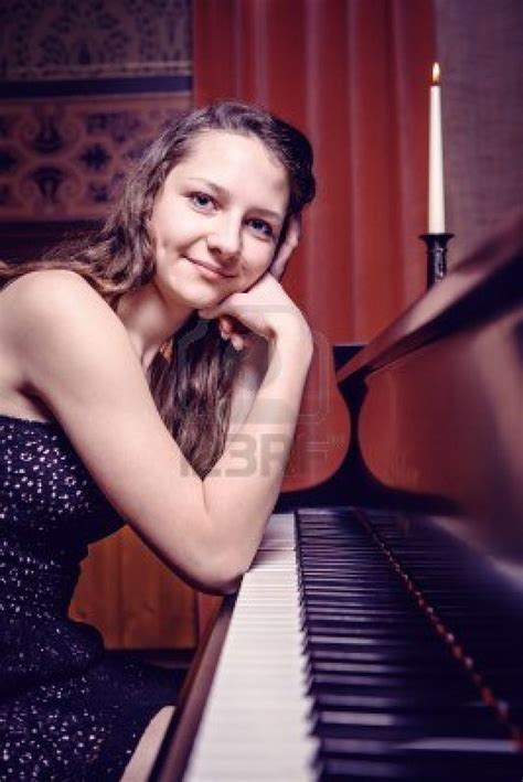 A Woman Sitting At A Piano Posing For The Camera