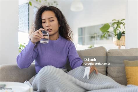 복통을 완화하기 위해 진통제를 복용하는 아시아 아픈 여자는 아침에 침대에 앉아 있습니다 고열로 침대에 누워있는 아픈 여자 감기
