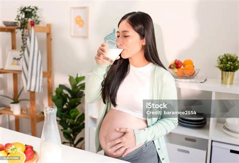 신선한 우유 한 잔을 들고 부엌 방에 서있는 젊은 아시아 임산부 출산 근처까지 임신 중에 건강을 유지하기 위해 먹는 것 과일에 대한 스톡 사진 및 기타 이미지 Istock