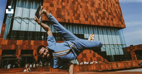 검은 재킷과 파란색 데님 청바지를 입은 남자가 낮에 갈색 벽돌 건물 근처에 서 있다 사진 Unsplash의 무료 안트베르펜 이미지