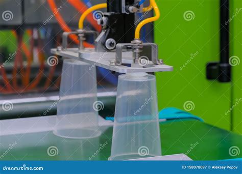 Cups On Conveyor Belt Of Plastic Injection Molding Machine With Robotic Arm Royalty Free Stock