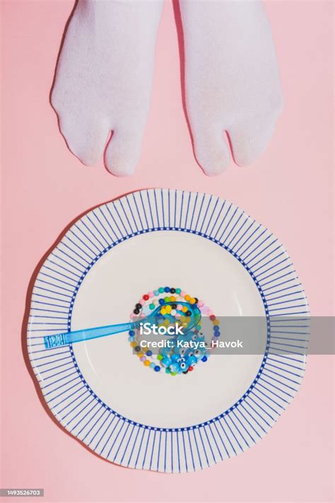 하얀 버선 양말을 신은 발은 분홍색 배경에 접시에 음식 형태의 구슬이 달린 색깔의 목걸이 근처에 서 있다 창조적 인 개념 평평한