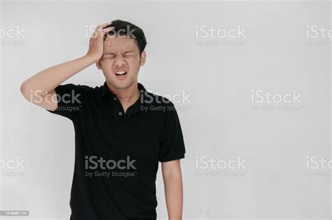 심한 두통으로 고통받는 회색 배경에 고립 된 젊은 아시아 남자의 초상화 사원에 손가락을 누르고 무력한 얼굴 표정으로 통증을
