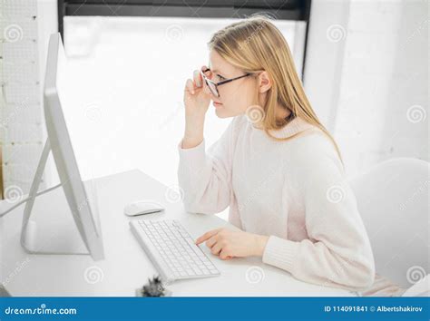 Woman Working In Office Sitting At Desk Using Computer And Looking On