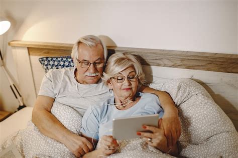 Free Photo High Angle View Of Senior Couple Using Touchpad While Resting In Bedroom