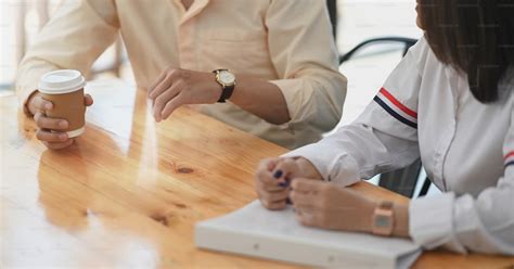 문서 파일을 들고 잘린 젊은 부부는 작업을 마친 후 휴식을 취하고 편안한 카페를 배경으로 나무 작업 책상에 함께 앉아 있습니다