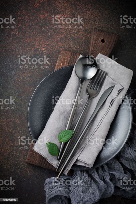 검은 색 강철 칼은 포크 칼 숟가락을 회색 린넨 냅킨과 검은 세라믹 접시에 놓습니다 선택적 초점 복사 공간이있는 소박한 빈티지 스타일의 메뉴 배경 개체 그룹에 대한 스톡