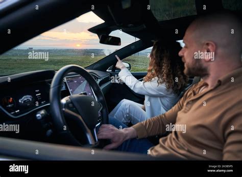 Stylish Young Woman Sitting On Passenger Seat And Pointing Finger At