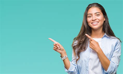 웃 고 옆에 두 손과 손가락으로 가리키는 카메라 보고 격리 된 배경 위에 젊은 아름 다운 아랍 여자 가리키기에 대한 스톡 사진