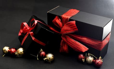 검은색 포장지에 빨간 리본과 활이 있는 다양한 모양의 선물 구성 측면보기 공간을 복사합니다 프리미엄 사진