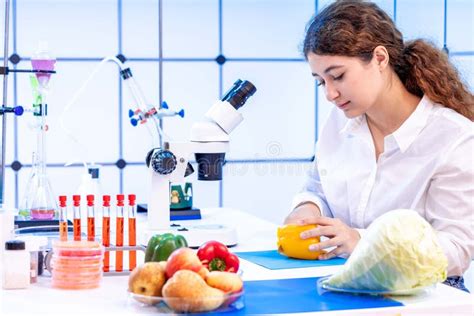 Young Woman In A Food Quality Control Laboratory Examining Samples Of Fruits And Vegetables For