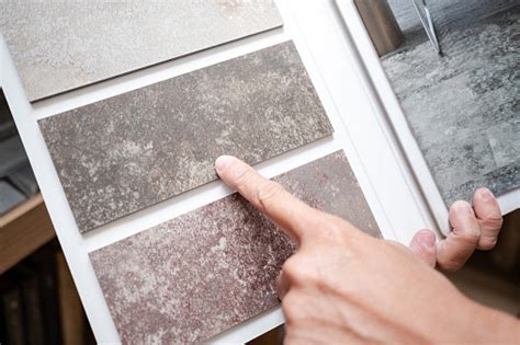 바닥재 재료 디자인 컬렉션 디스플레이 카탈로그의 석재 타일 샘플을 가리키는 디자이너 손 가정 디자인 상점에서 바닥 마감을 위해 거친 질감과 패턴을 선택하는 고객 가리키기에