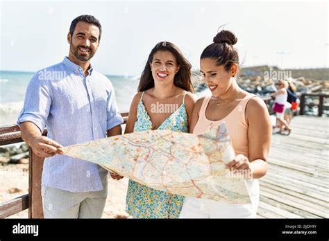 Trois jeunes amis hispaniques souriant recherchent un itinéraire sur la