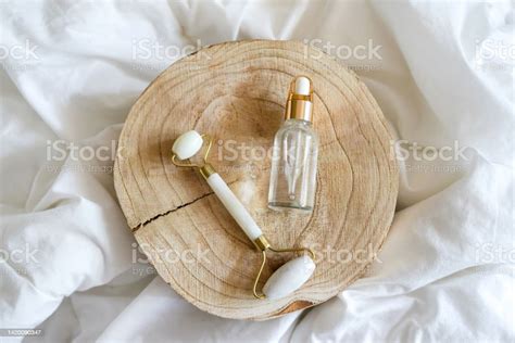 가정용 스킨 케어 및 스파를위한 화장품 얼굴 키트 얼굴 롤러 Gua Sha 마사지기 흰색 침대 배경에 나무에 에센셜 오일 또는 세럼 병 자연 치료 개념 플랫 레이 가정