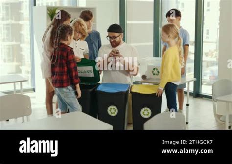 Male Teacher Shows To The Pupils How And Where Sort Rubbish Correctly