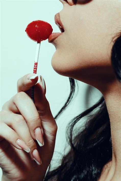 빨간 막대 사탕을 든 여성의 클로즈업 · 무료 스톡 사진