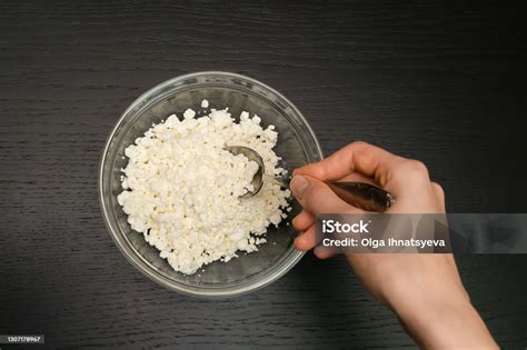 숟가락을 든 여성의 손은 검은 색 테이블에 유리 그릇에서 코티지 치즈 한 알갱이를 가져갑니다 개념에 대한 스톡 사진 및 기타