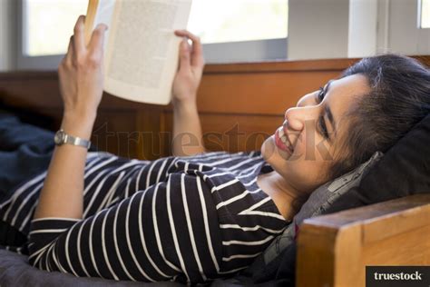 Young Woman Lying Down Reading By Spid Pye Truestock