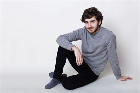 잘 기쁘게 헤이젤 눈 소년 어두운 수염과 콧수염 짙은 검은 눈 썹 실내 자신감 식은 데 편안 하 게 바닥에 앉아 캐주얼 옷을 입고 세련 된 헤어스타일 관능에 대한 스톡 사진