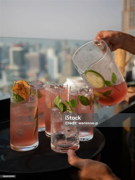 상쾌하 고 갈증을 끄는 핑크 레모네이드 Mocktail 서버 옥상 바에서 도시 도시 스카이 라인 배경으로 붓는 다 따르기에 대한