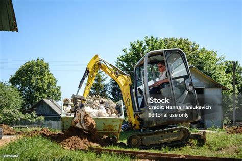 민스크 벨라루스 2024년 5월 24일 미니 굴삭기는 토양에 도랑을 파고 있습니다 굴삭기 운전자가 버킷을 제어합니다 크롤러 머신 토공 장비 굴착 건설 현장에서 굴착 작업