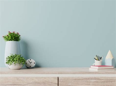 A White Vase Sitting On Top Of A Wooden Table Next To A Plant And Two Books