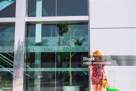 인터넷 메시지와 함께 휴대 전화를 사용 하 여 공항 밖에 서 아름 다운 젊은 여성 개인정보와 서 좋은 사람에 대 한 비즈니스 또는 휴가 여행 개념 색된 드레스와 긴 곱슬