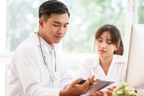아시아의 젊은 의사 독서 정보를 확인 하 고 청진 기 및 컴퓨터 책상을 착용 하 여 여성 환자 검사 실에 치료의 좋은 소식