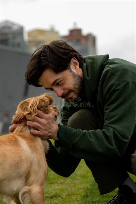 The Man Leaned Over To The Cocker Spaniel And Scratched Behind His Ears A Bearded Brunette Man