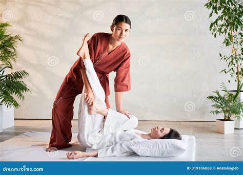 Masseuse Making Thai Yoga Massage Treatment Stretching Female Patient