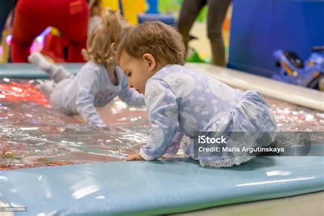 드레스를 입은 작은 귀여운 아기 유아 소녀는 보육원 놀이방의 어린이 놀이터에 있는 장난감 수영장에 앉아 있으며 부드러운 초점 블러의 배경 2명에 대한 스톡 사진 및 기타