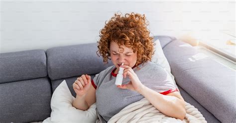 여자는 알레르기가 있고 그녀는 자신을 돕기 위해 비강 스프레이를 사용하고 있습니다 비강 스프레이를 사용하는 여성 감기에 도움이되는 비강 스프레이 코가 뚝뚝 떨어지는