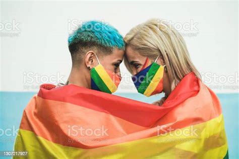젊은 커플 의 레즈비언 여자 아래 Lgbt 무지개 플래그 착용 마스크 에 게이 자부심 퍼레이드 왼쪽 소녀 귀에 초점 2명에 대한 스톡 사진 및 기타 이미지 Istock