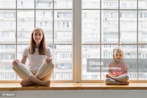 젊은 어머니는 창 앞에서 3 살 짜리 딸과 함께 요가를하고 있습니다 행복한 엄마 미소 동안 연습 요가 함께 그녀의 귀여운 소녀 2명에 대한 스톡 사진 및 기타 이미지