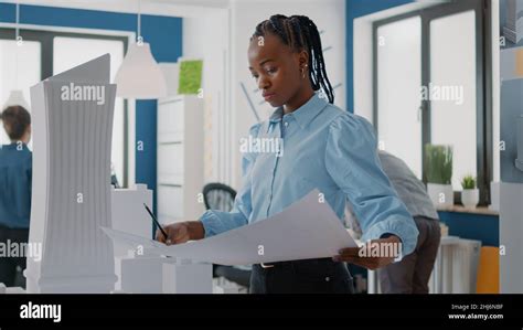 Woman Architect Analyzing Building Model And Blueprints Plans For Project Development