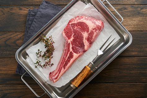 신선한 토마 호크 생 스테이크 오래된 나무 배경에 허브와 소금을 곁들인 건조 숙성 생 토마호크 쇠고기 스테이크 그릴 준비 평면도