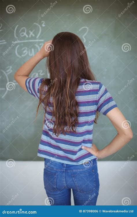 Rear View Of Schoolgirl Pretending To Be A Teacher In Classroom Stock
