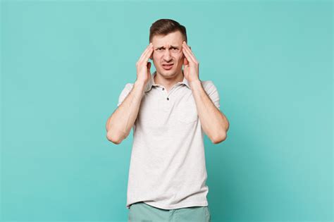 두통을 가진 우연한 옷에 불쾌 한 젊은 남자를 소진 사원에 손을 넣어 머리는 파란색 청록색 배경에 고립 사람들은 진심으로 감정 라이프 스타일 개념입니다 복사 공간을 모의