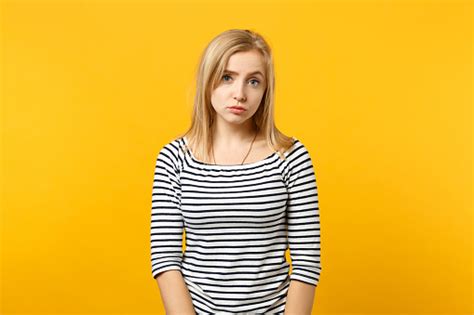 스튜디오에서 노란 주황색 배경에 고립 된 줄무늬 옷을 입고 서 있는 젊은 여자의 불쾌 한 화가의 초상화 사람들은 진심으로 감정 라이프 스타일 개념입니다 복사 공간을 모의