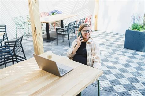 Premium Photo Cute European Woman Sitting At Outdoor Cafe Table With Laptop And Cup Of Coffee
