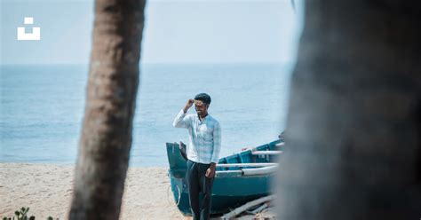 Foto Un Hombre Parado En Una Playa Junto A Un Barco Imagen Azul