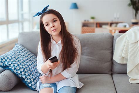 행복 한 초반 소녀 Tv를 시청 하 고 아늑한 소파에 집에서 휴식 라이프 스타일 평범한 주말 및 아이 개념입니다 소녀에 대한