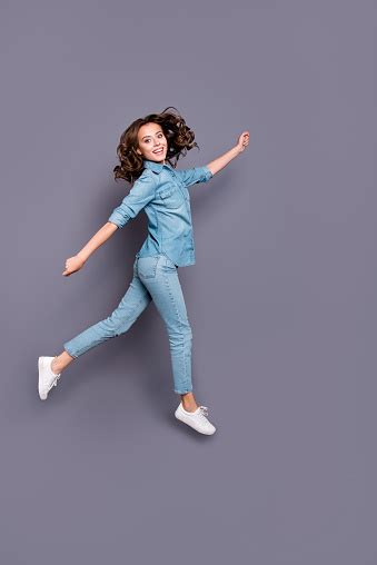좋은 미친 세련 된 쾌활 한 매력적인 귀여운 여자 캐주얼 데님 셔츠에 청바지 물결 모양 머리 속이 고 공기 가의 전신 크기 길이 회색 배경 위에 절연 달리기에 대한 스톡