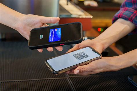 결제 계좌용 Qr코드로 전화기에 서 있는 베이커리 직원 송금 결제를 원하는 고객 고객은 Qr 코드를 스캔하여 휴대폰을 넘겨 신용 카드로 결제합니다 체크 표시 화면 신용