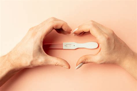 임신 테스트 키트 여성의 손은 분홍색 배경에 실크 리본으로 긍정적 인 임신 검사를 개최합니다 의료 의료 부인과 임신 불임 출산