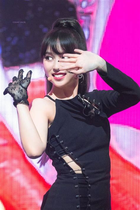 A Woman In A Black Dress Holding Her Hand Up To Her Face With Both Hands