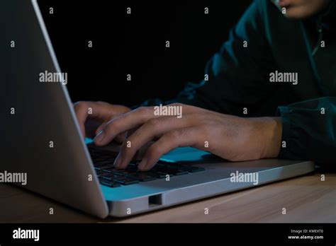 asian hacker hacking computer network with laptop in dark cyber