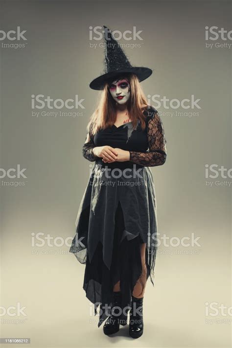회색 배경 위에 서 모자와 마녀 할로윈 의상에 고딕 양식의 젊은 여자 마녀 또는 죽은 신부의 카니발 의상에 여자 무서운 할로윈