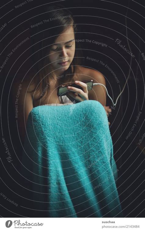 Girl Sits Wrapped In A Blanket And Looks Into Her Smartphone A